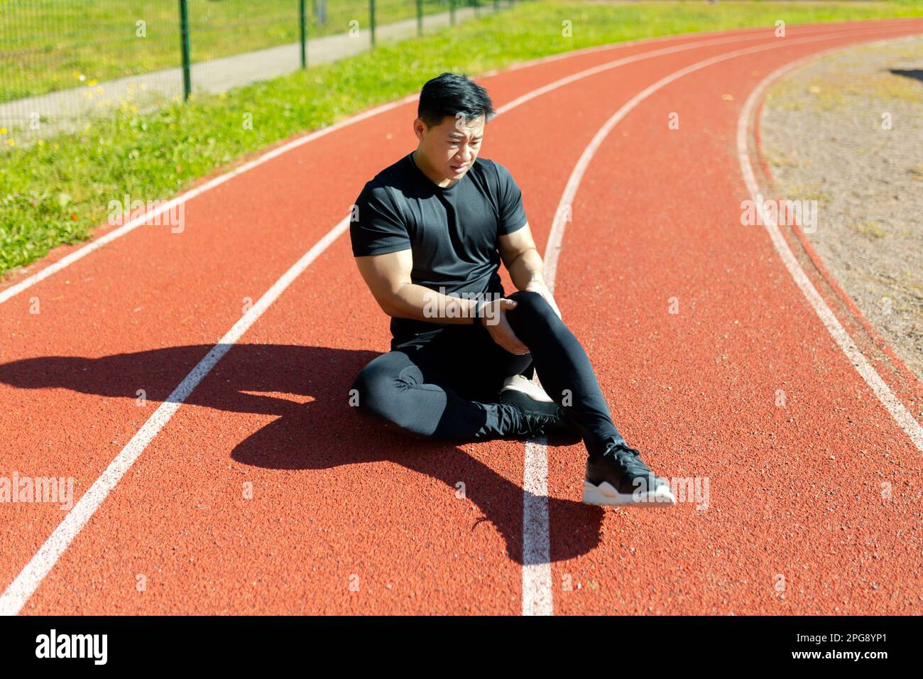 Sports injury. A young Asian sportsman, athlete, runner sits on a ...