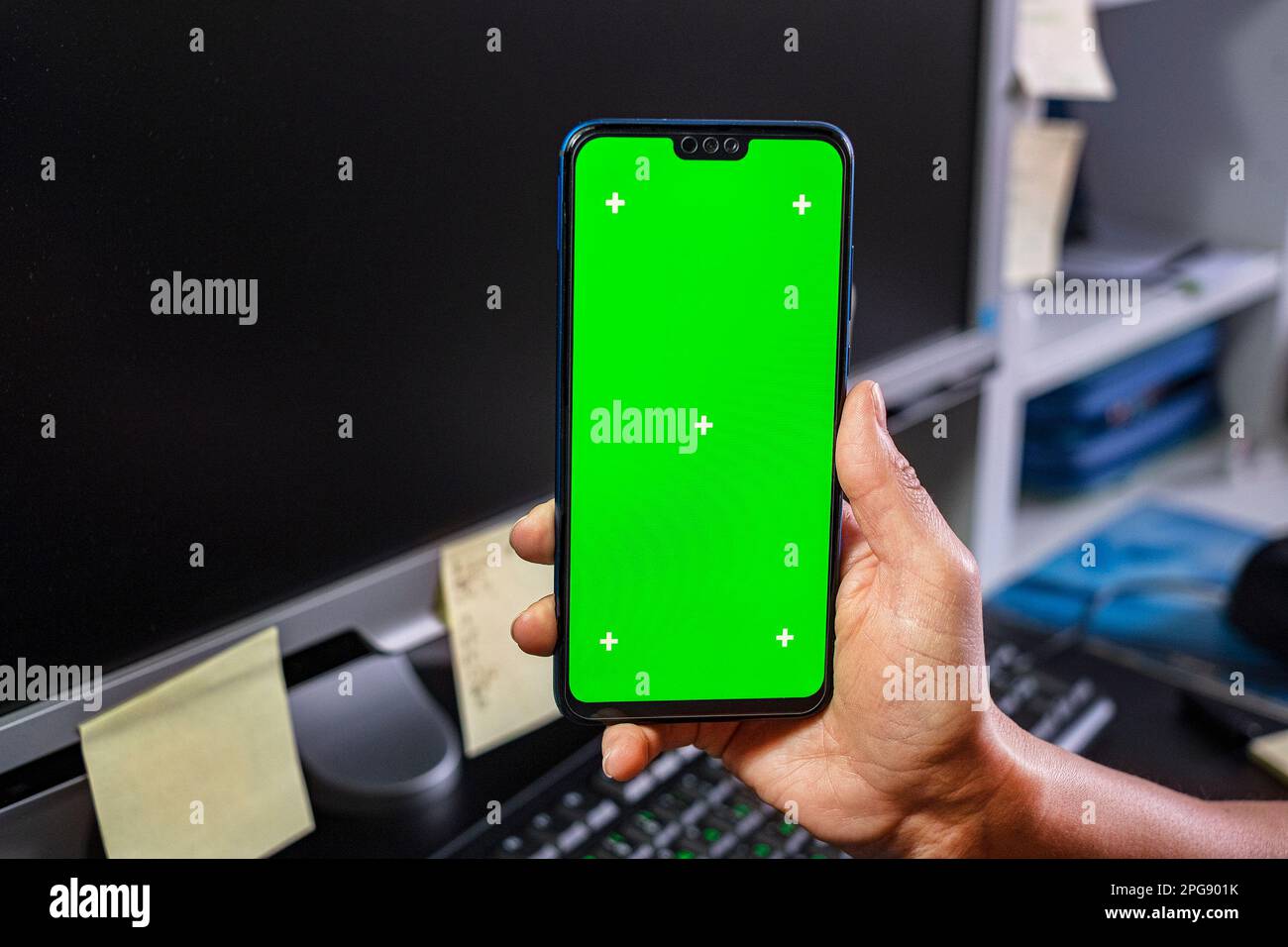 hands hold a smartphone with green screen of workspace background ...