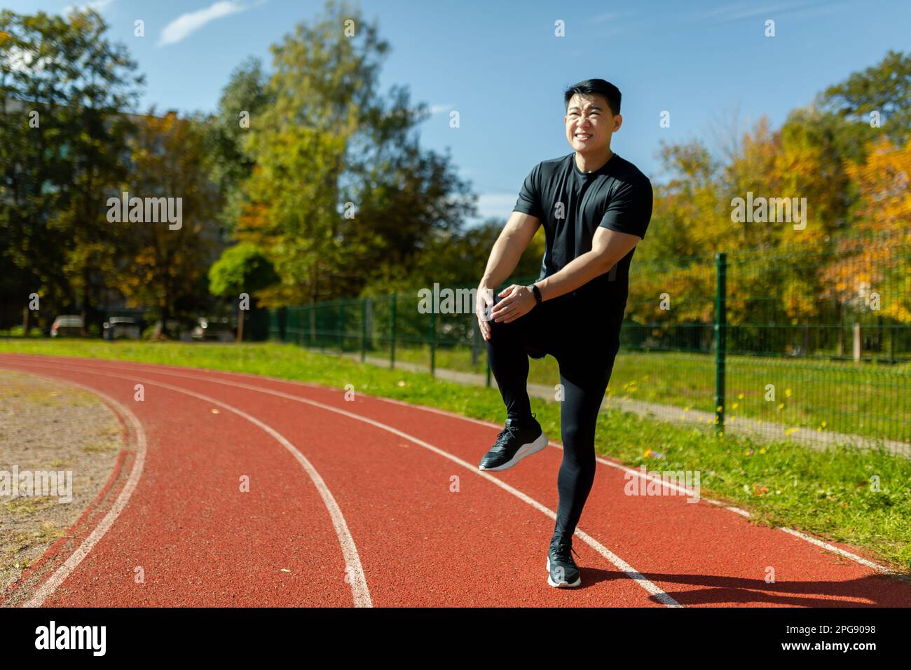 Sports injury. A young male athlete stands on a running track in a ...