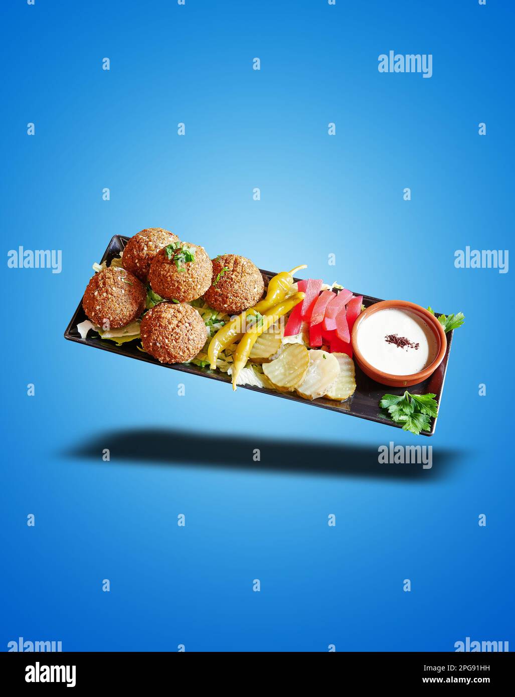 Floating Black plate with Falafel apetizer on blue gradient background ...