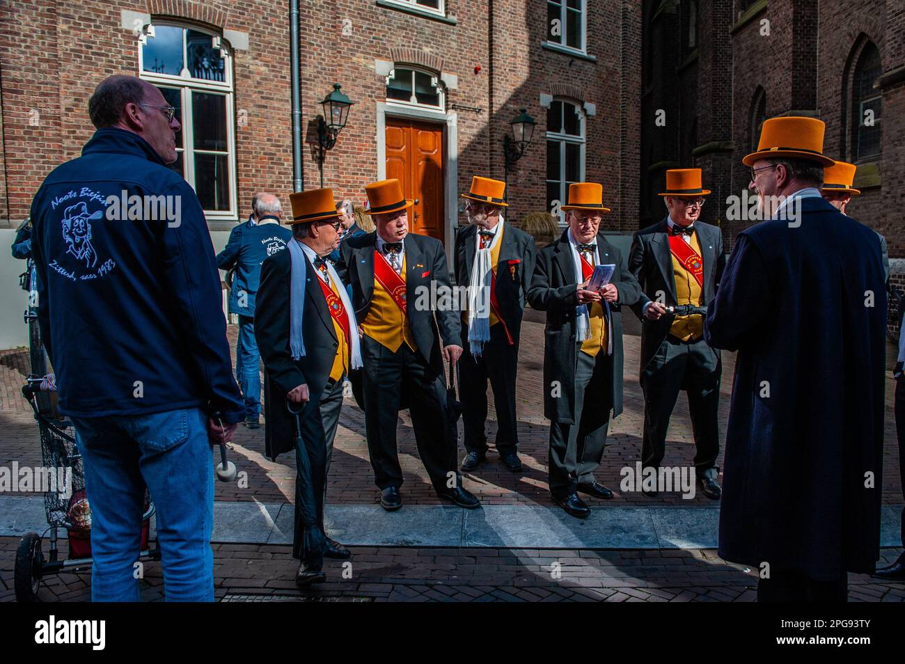 A group of men from the organization wearing black suits and orange ...