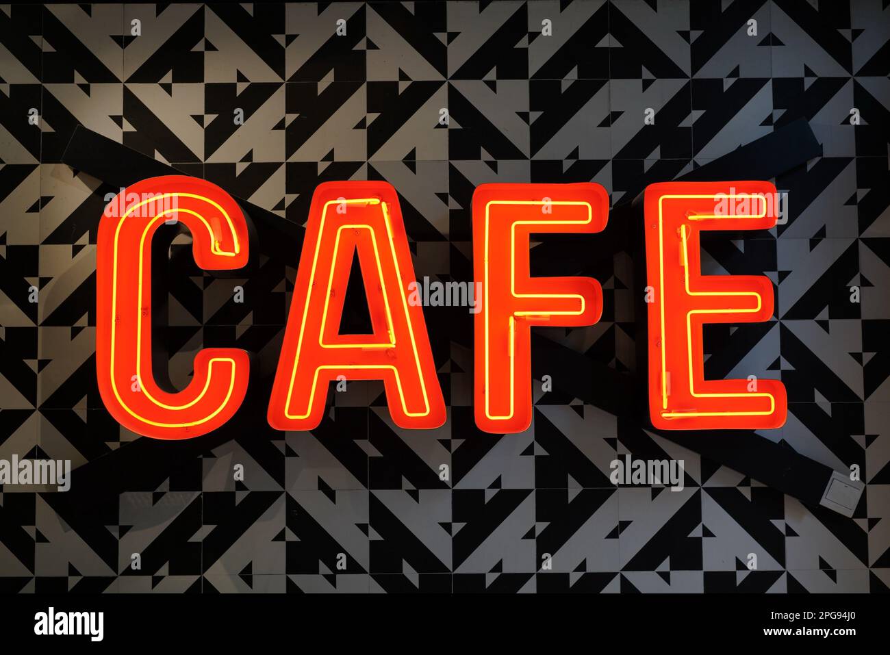 A brightly lit neon sign in the shape of the word "Cafe" surrounded by ...