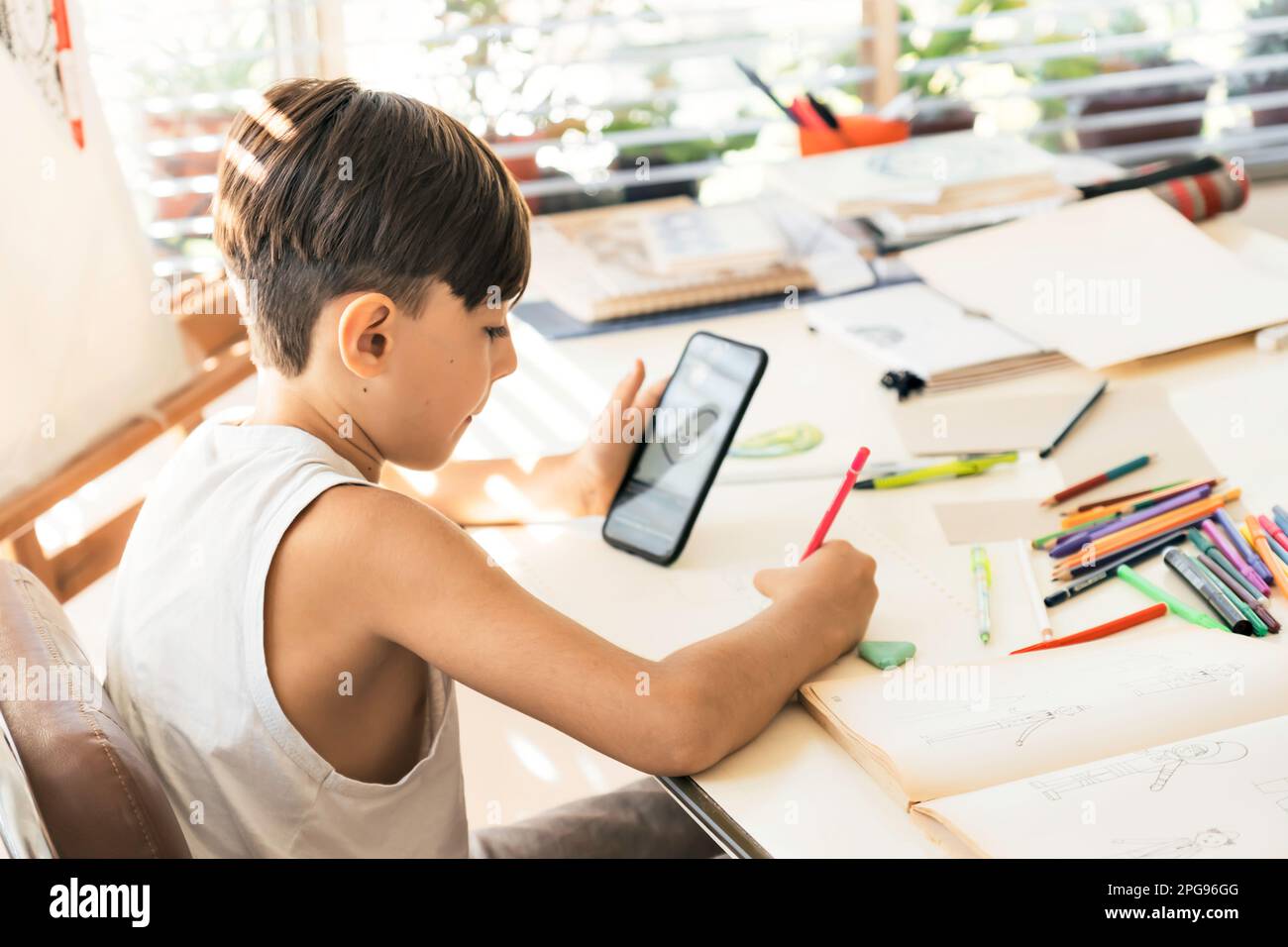 A boy is learning to draw with her smart phone. Online education ...