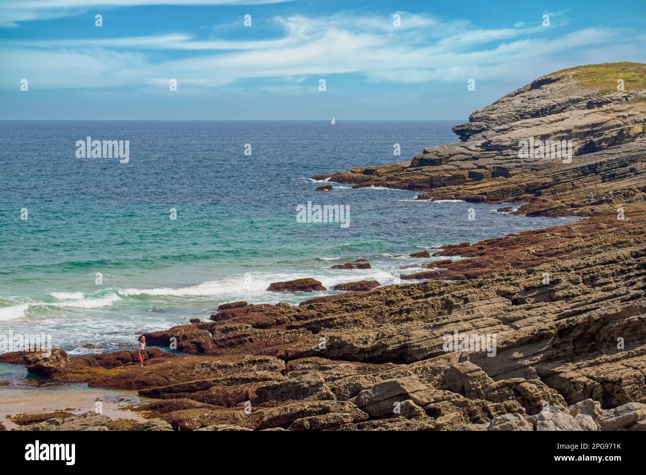 people walking on the rocks of the Sonabia cliff on the shore of the ...
