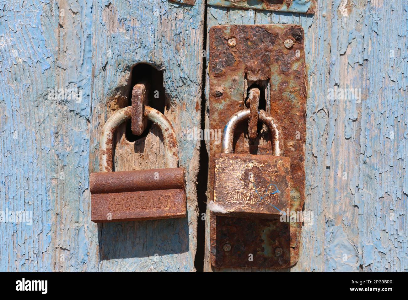 A rustic padlock is securely fastened onto a wooden door, with ...
