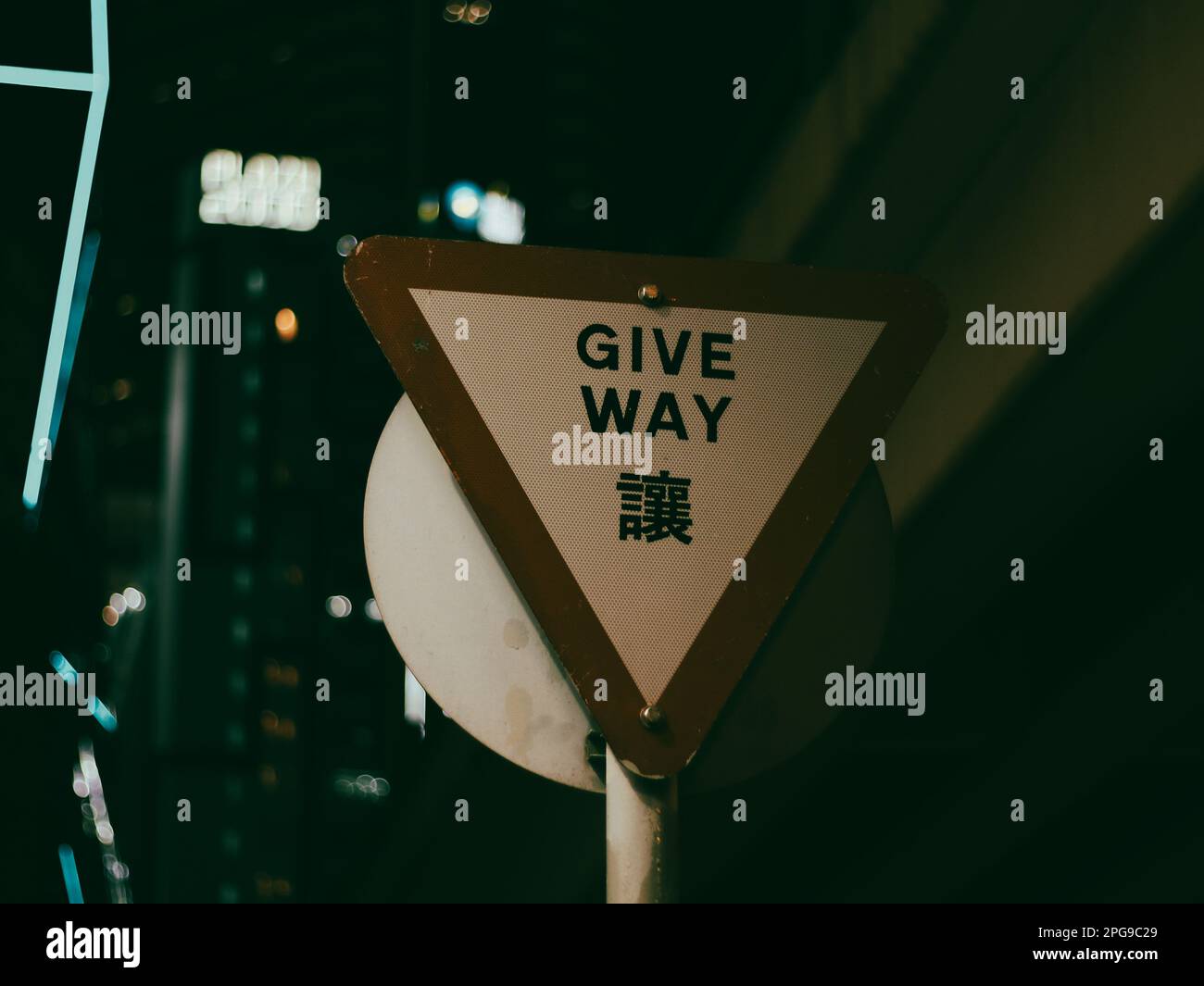 A close-up of a street sign in an urban setting that reads "Give Way at ...
