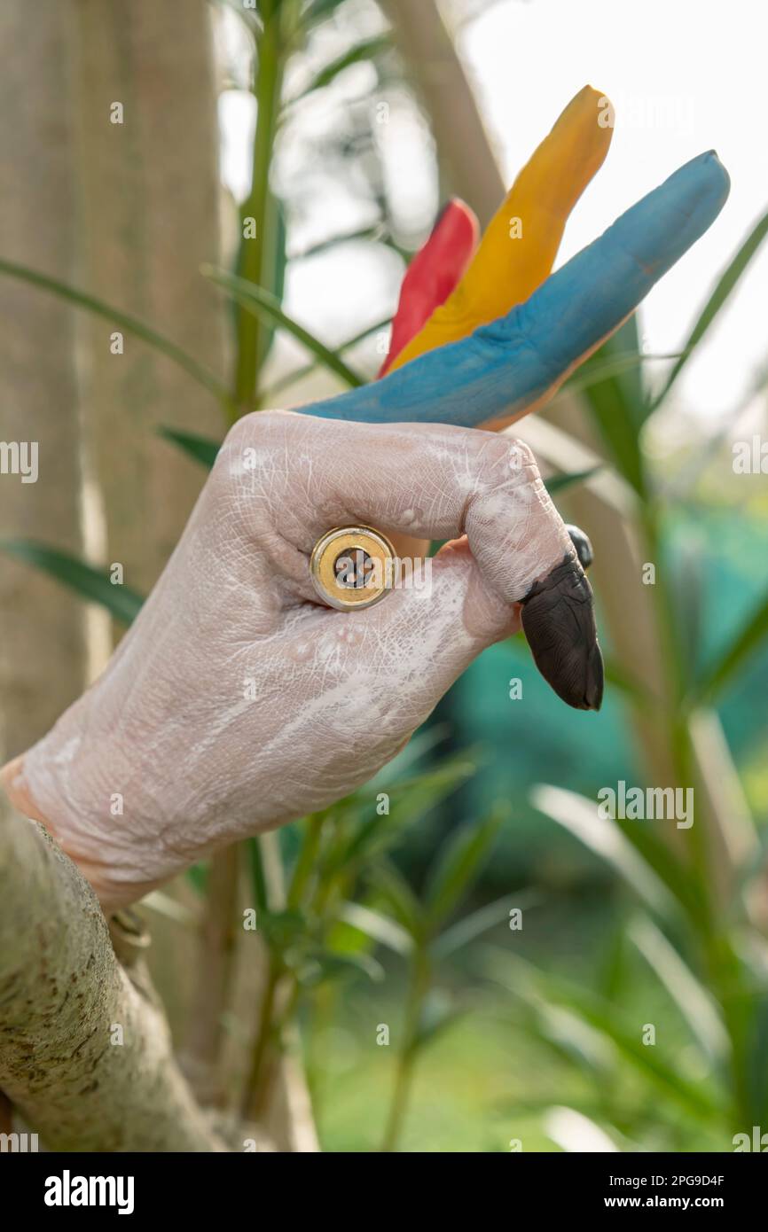 A female hand painted with various colors simulates the head of a ...