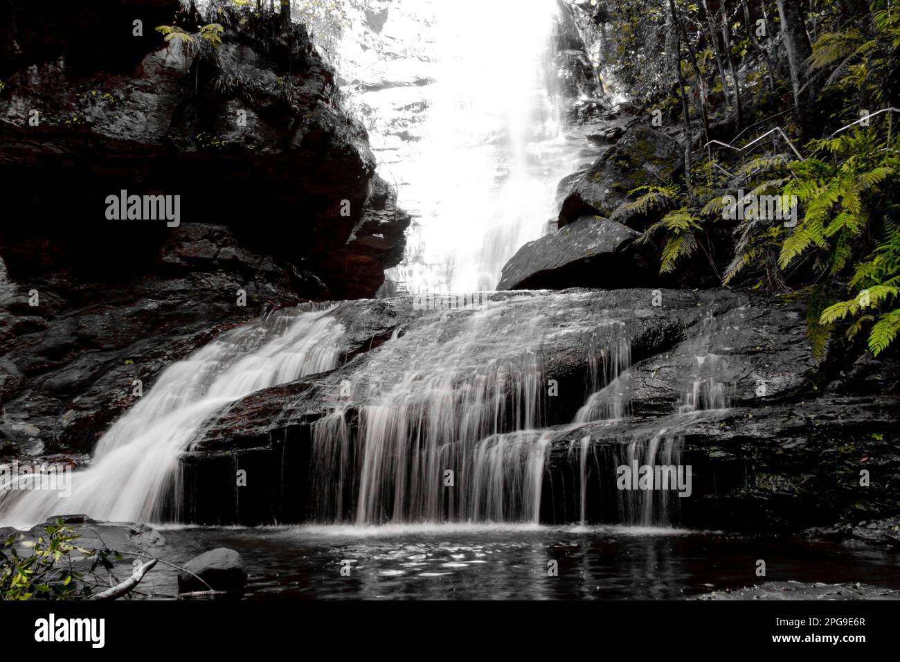 A scenic waterfall cascading down a rock wall into a tranquil pool ...