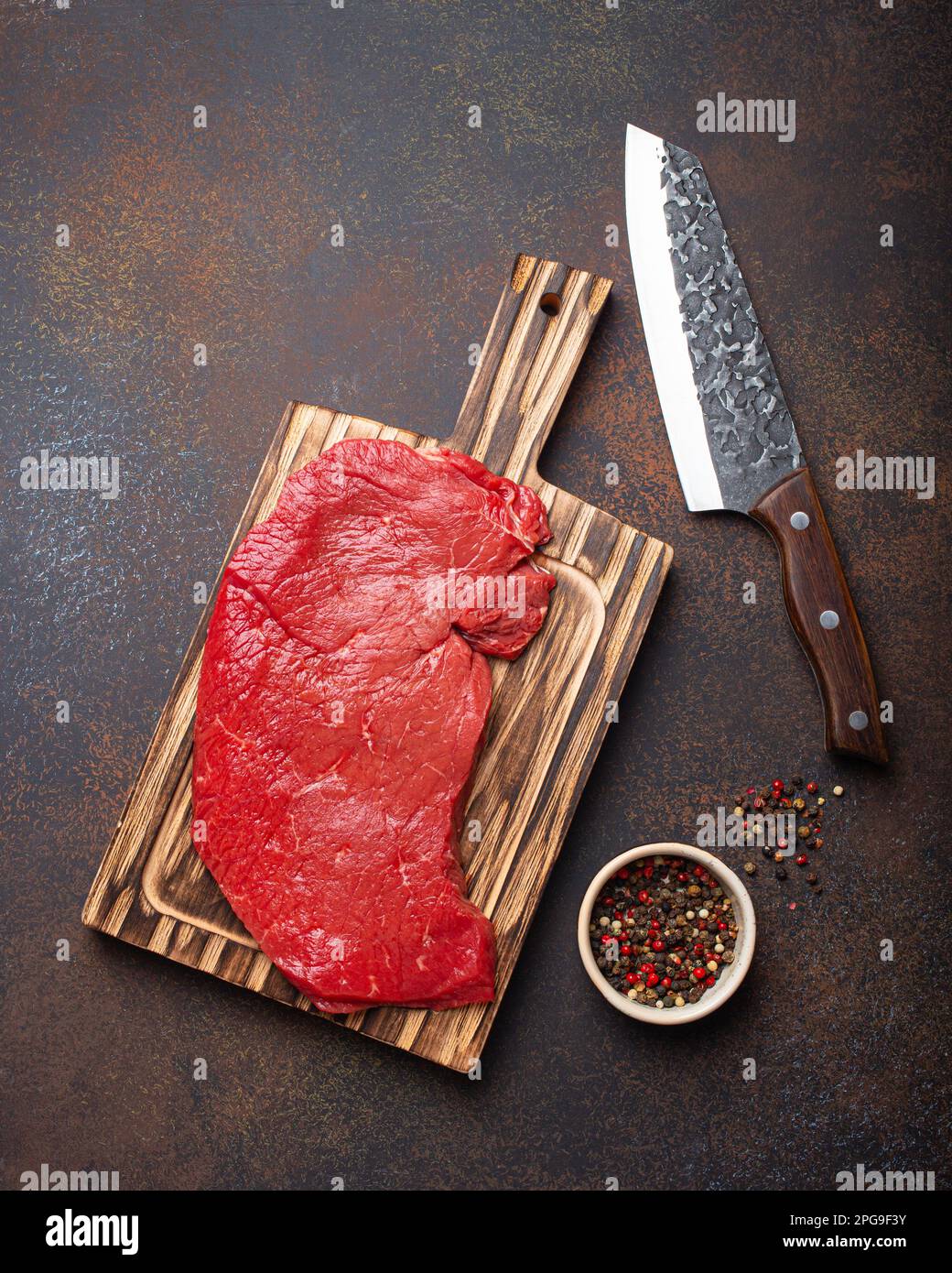 Raw uncooked top round beef steak on wooden cutting board with big ...