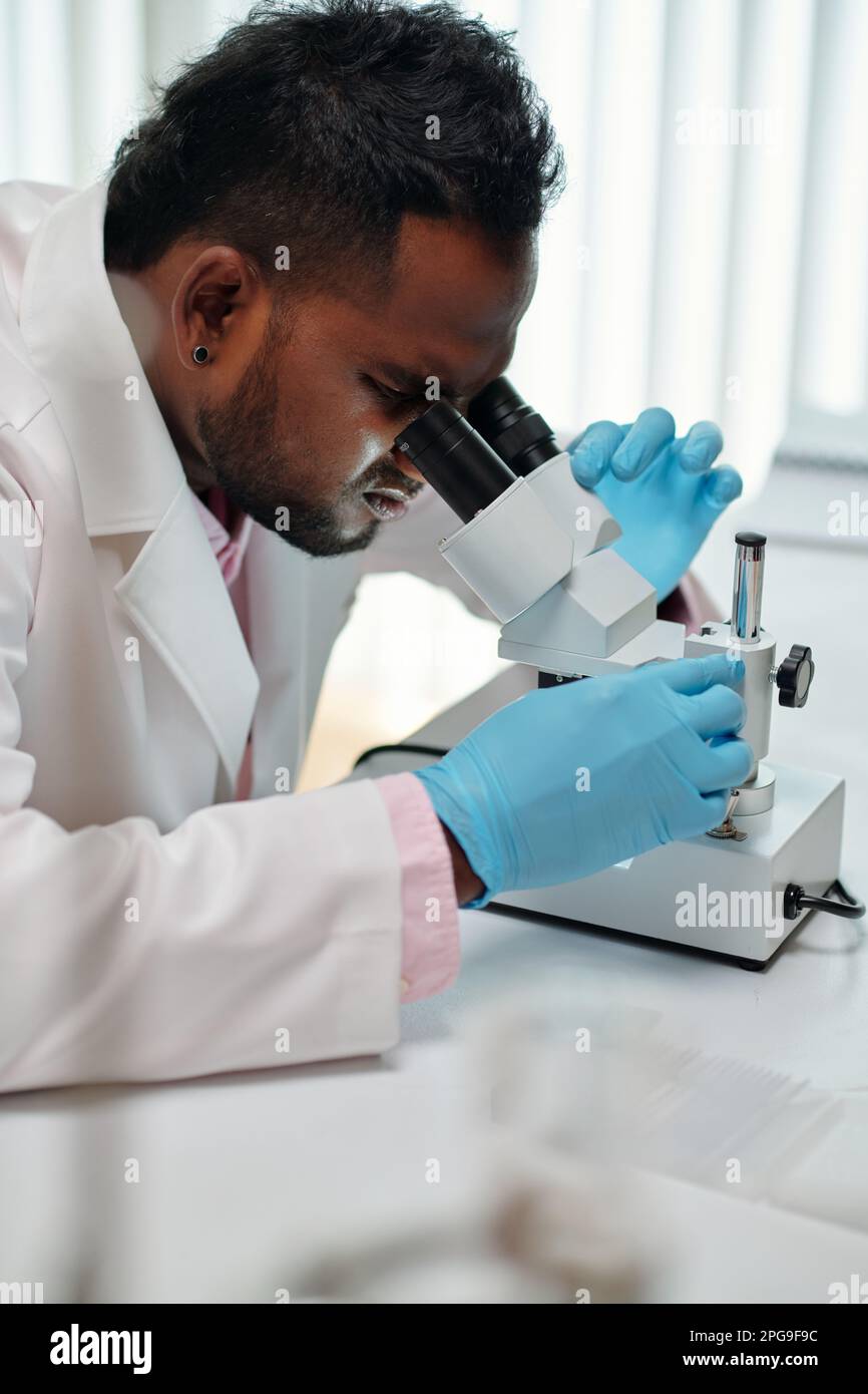 Side view of young African American male scientist looking in ...