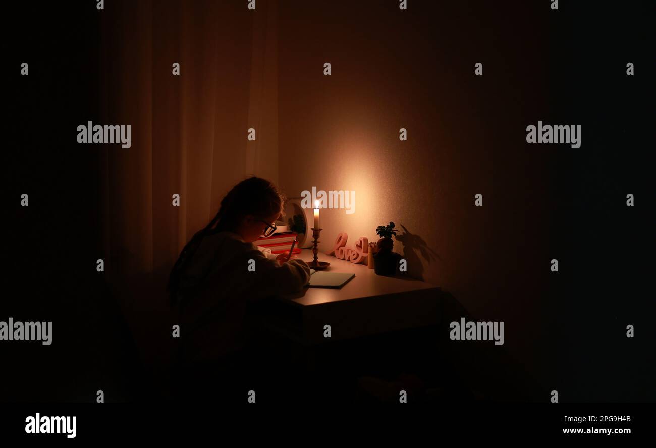 Schoolgirl uses candlelight to writes and reads in darkness without ...