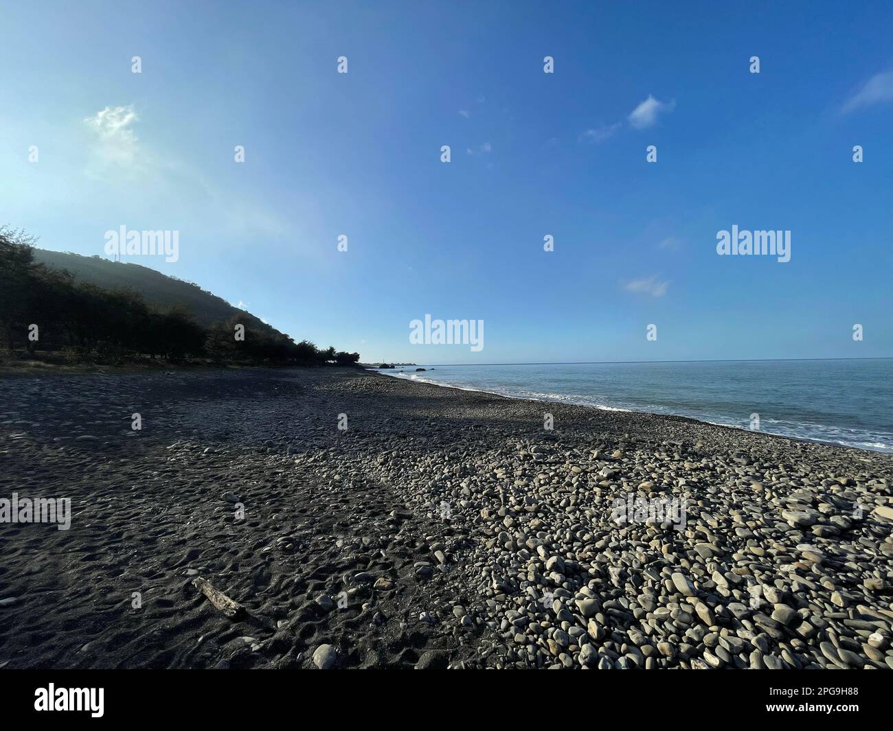 A vast expanse of black sand stretches across the horizon at the shore ...