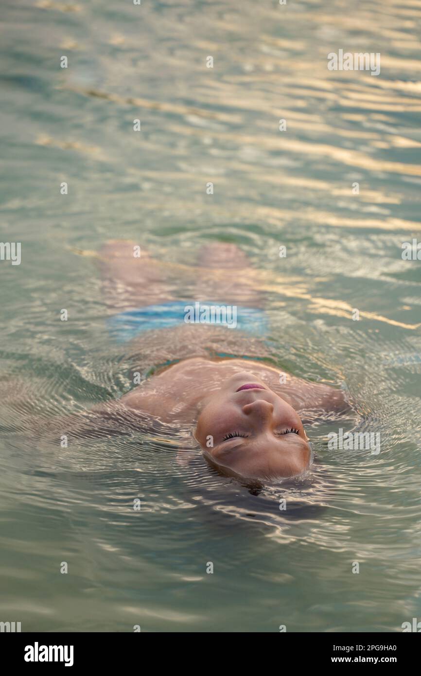 The boy lies in water on his back with closed eyes. Boy relaxing at ...