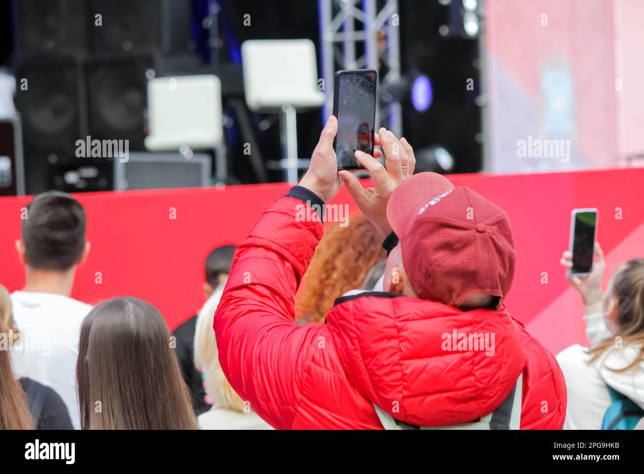 People at the concert joyfully raise their hands up. A man shoots an ...