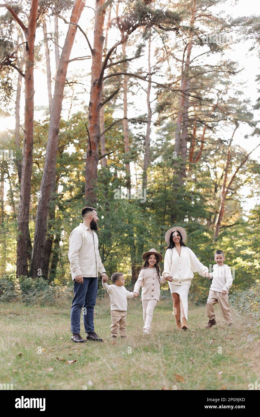 Young mother, father with daughter and sons are walking, having fun in autumn forest. Family ...