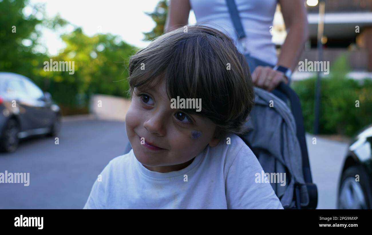 Happy adorable child seated on stroller smiling at camera. One little ...