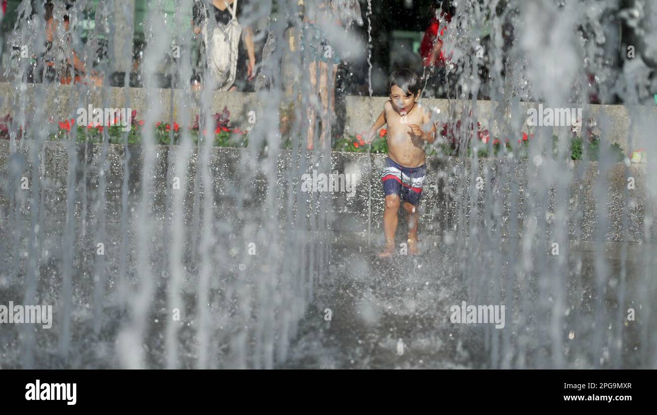 Little boy running at water jets in city park during summer day. Small ...