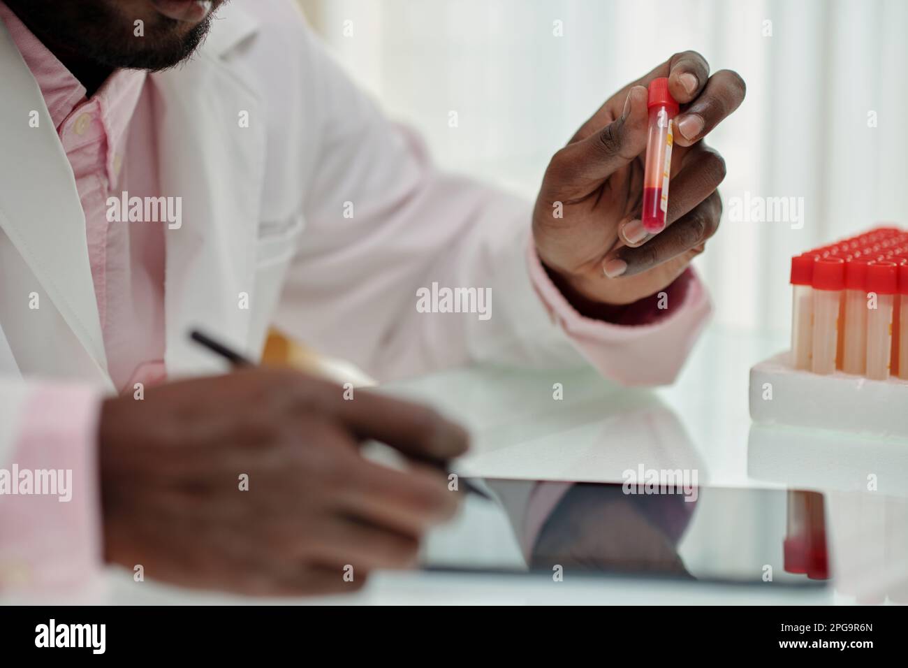 Hand of young African American clinician holding flask with blood ...
