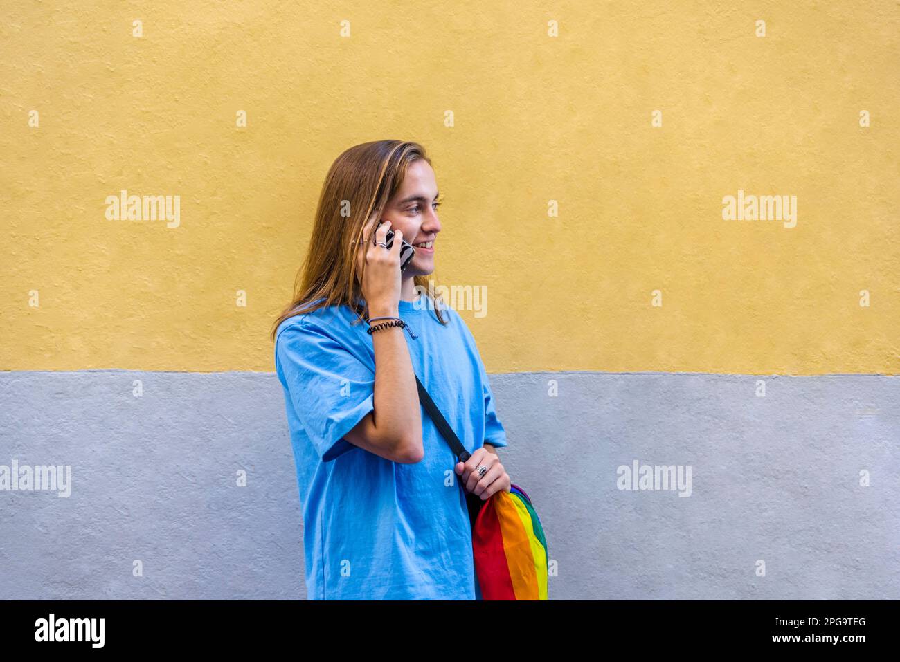Man talking on the phone while wearing a belt bag with the lgbt rainbow ...