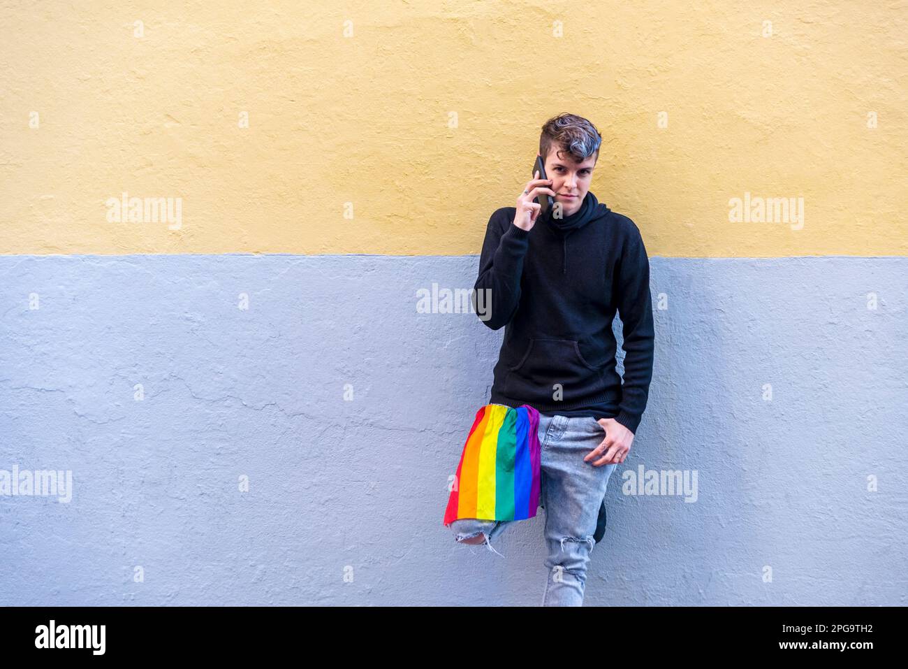 Non binary person with an lgbt rainbow flag talking on the phone ...