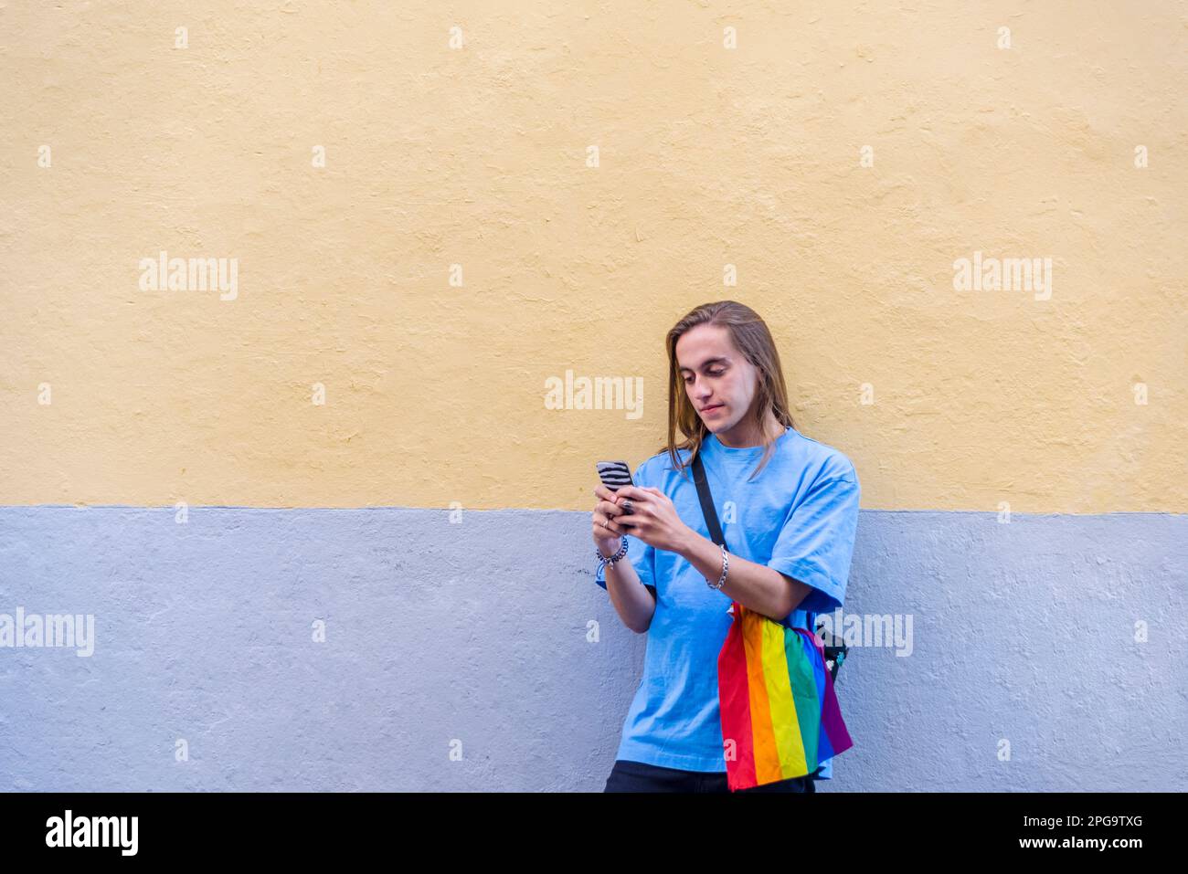Man using mobile phone while wearing a belt bag with the lgbt rainbow ...