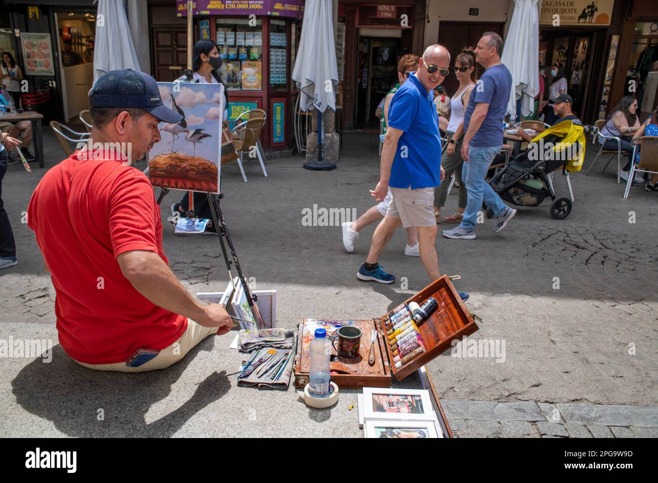 Street painter and restaurants bar tables and tourists dining along the ...