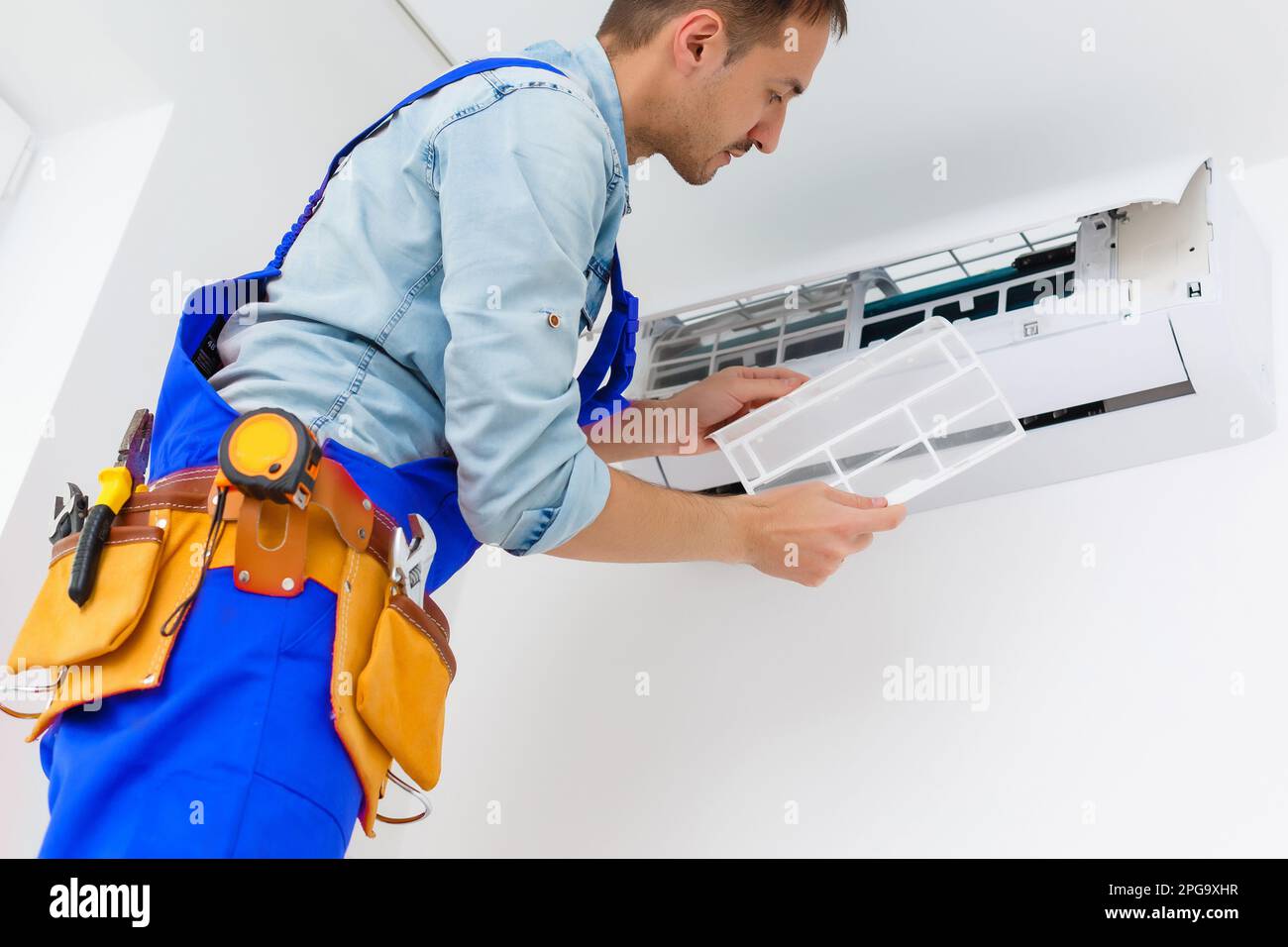 Male technician repairing air conditioner indoors Stock Photo - Alamy