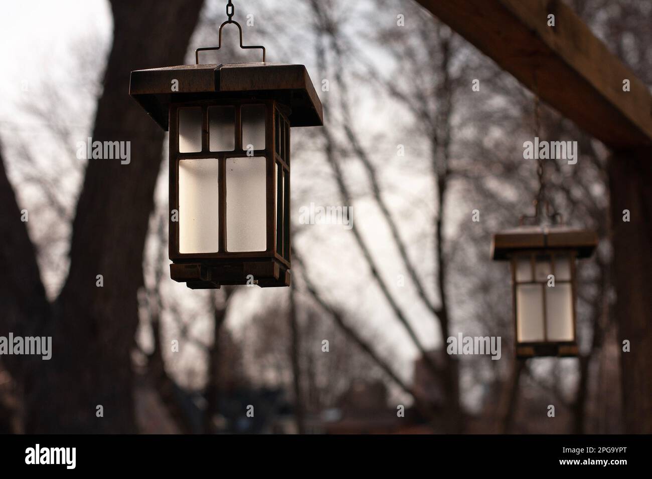 Two hanging lanterns are suspended from a wooden beam Stock Photo - Alamy