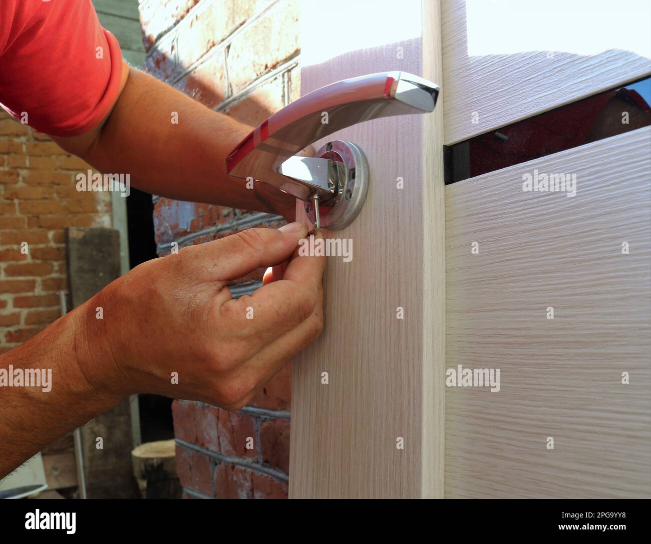 screwing a metal handle to a light door leaf close-up, installing the ...