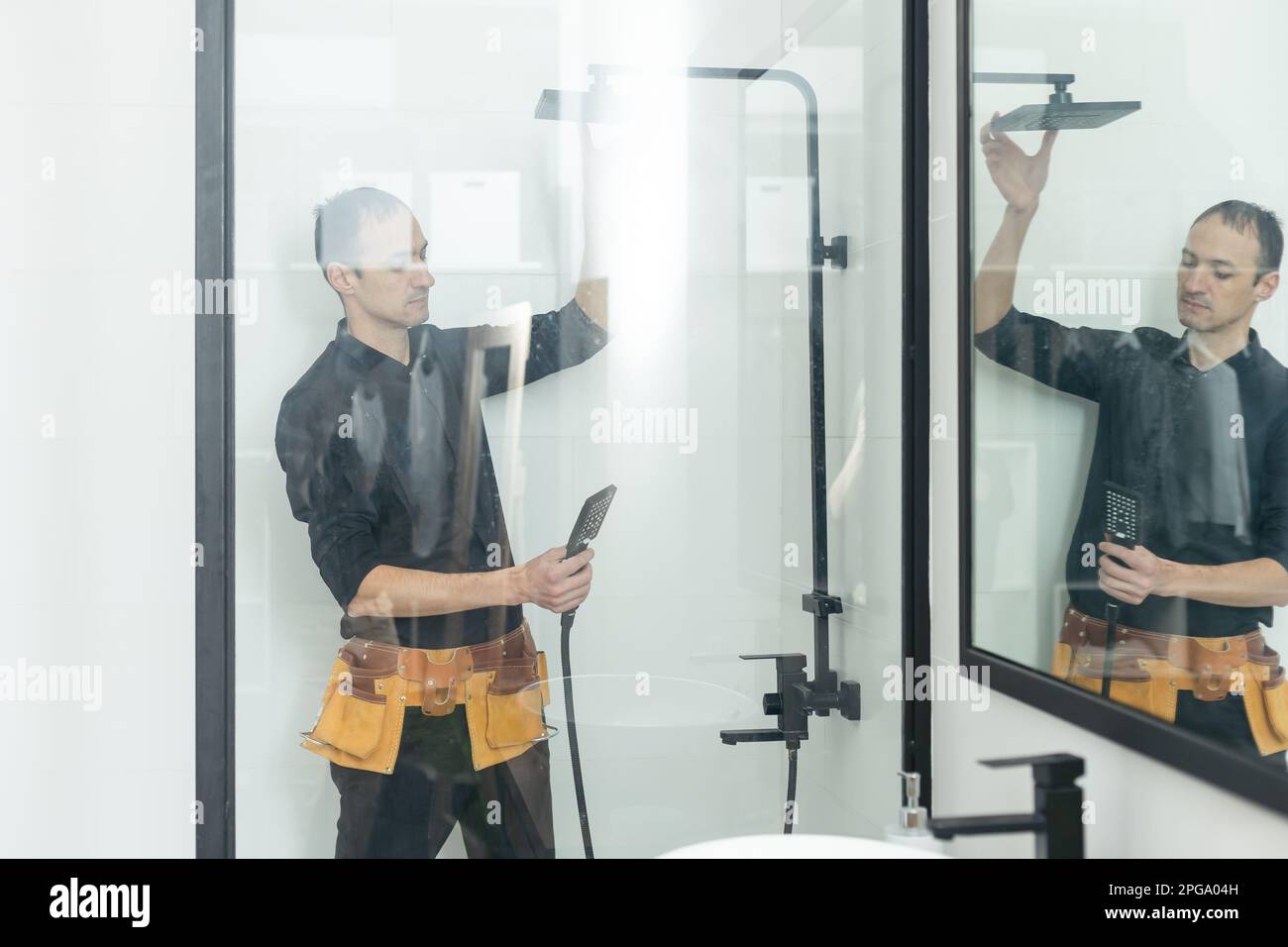 The worker is connecting the glass walls of the shower enclosure with a ...