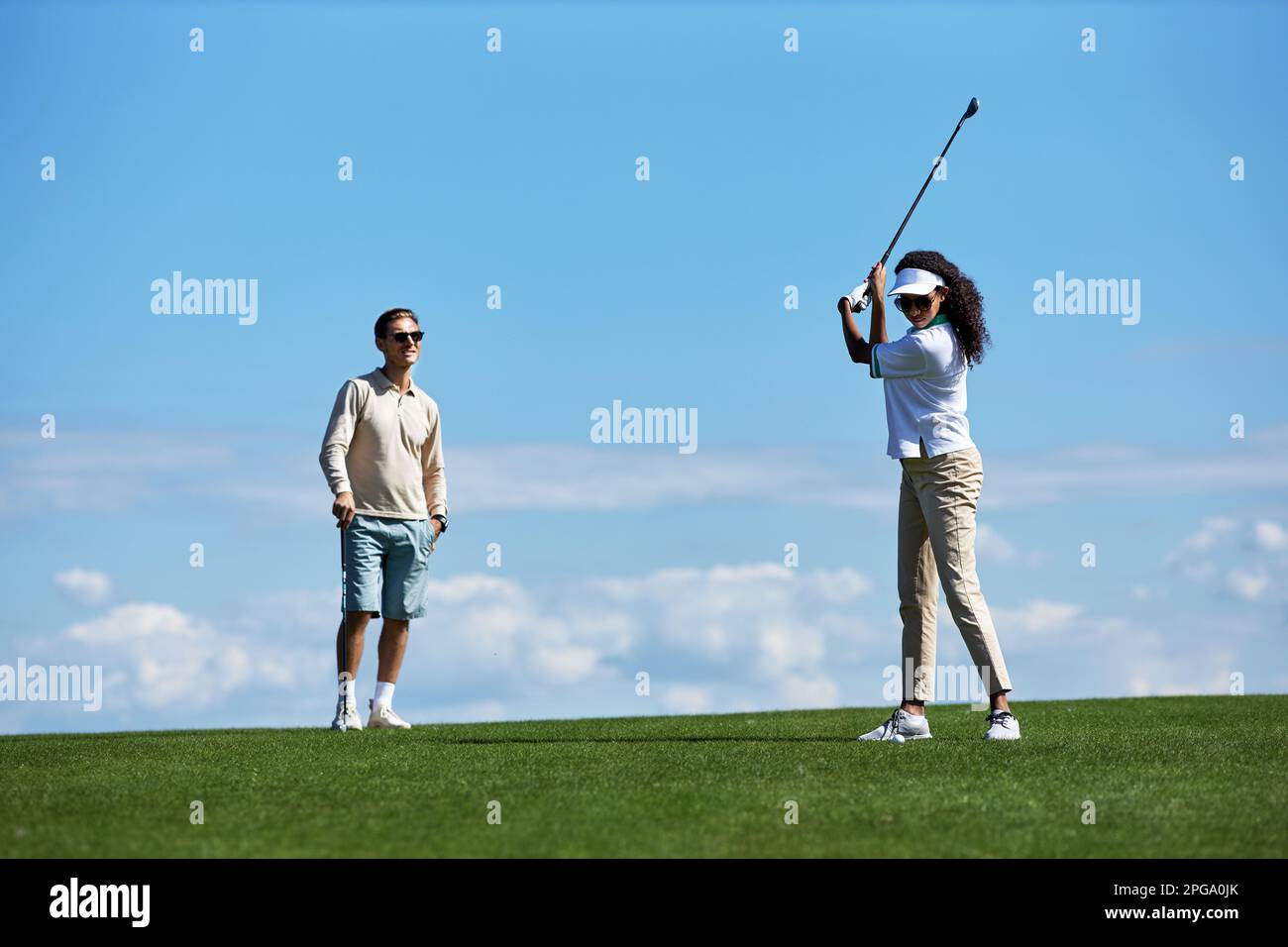 Full length portrait of active sporty couple playing golf against blue ...