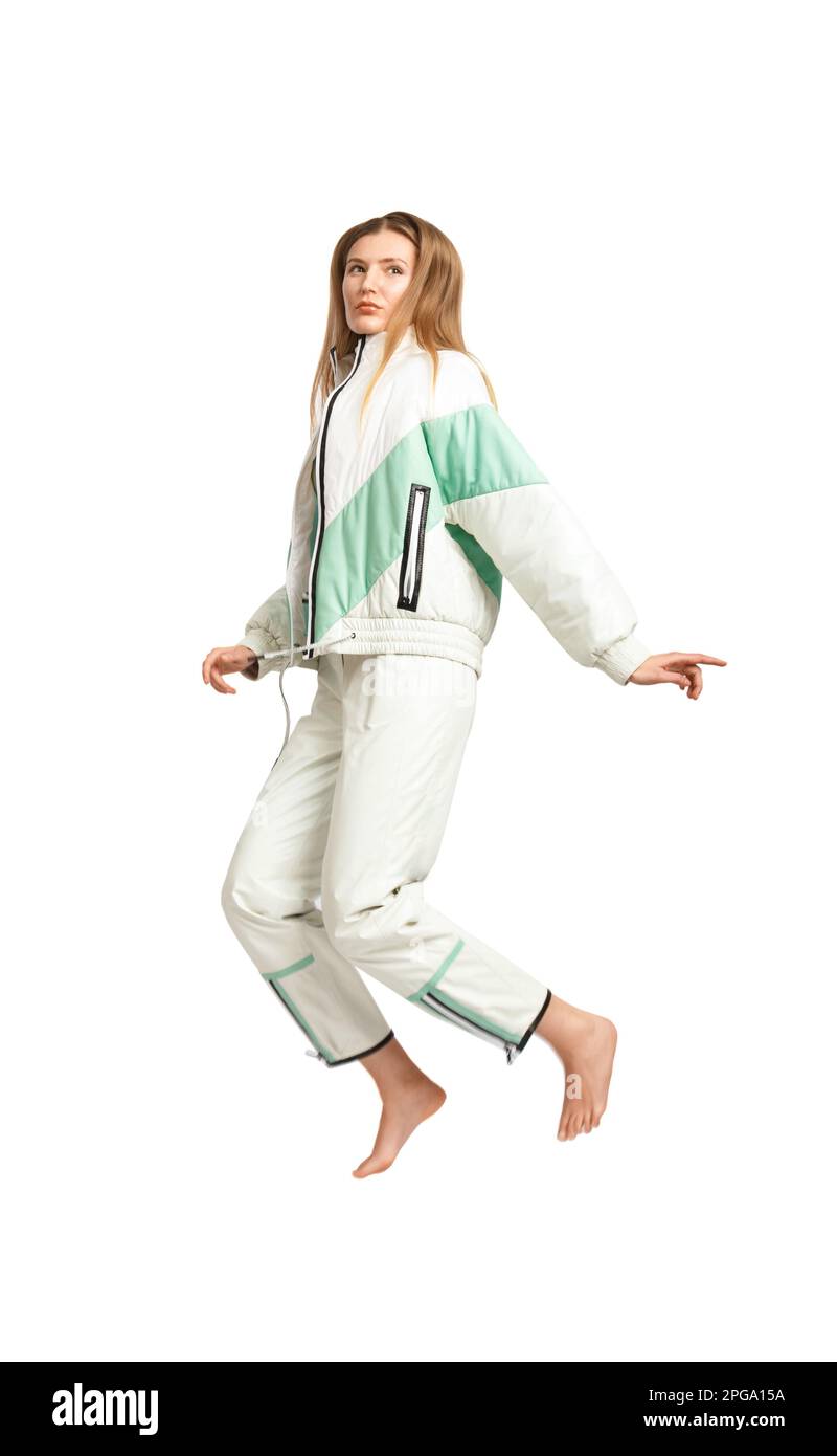 A girl in a fashionable light tracksuit for a walk poses on a white ...