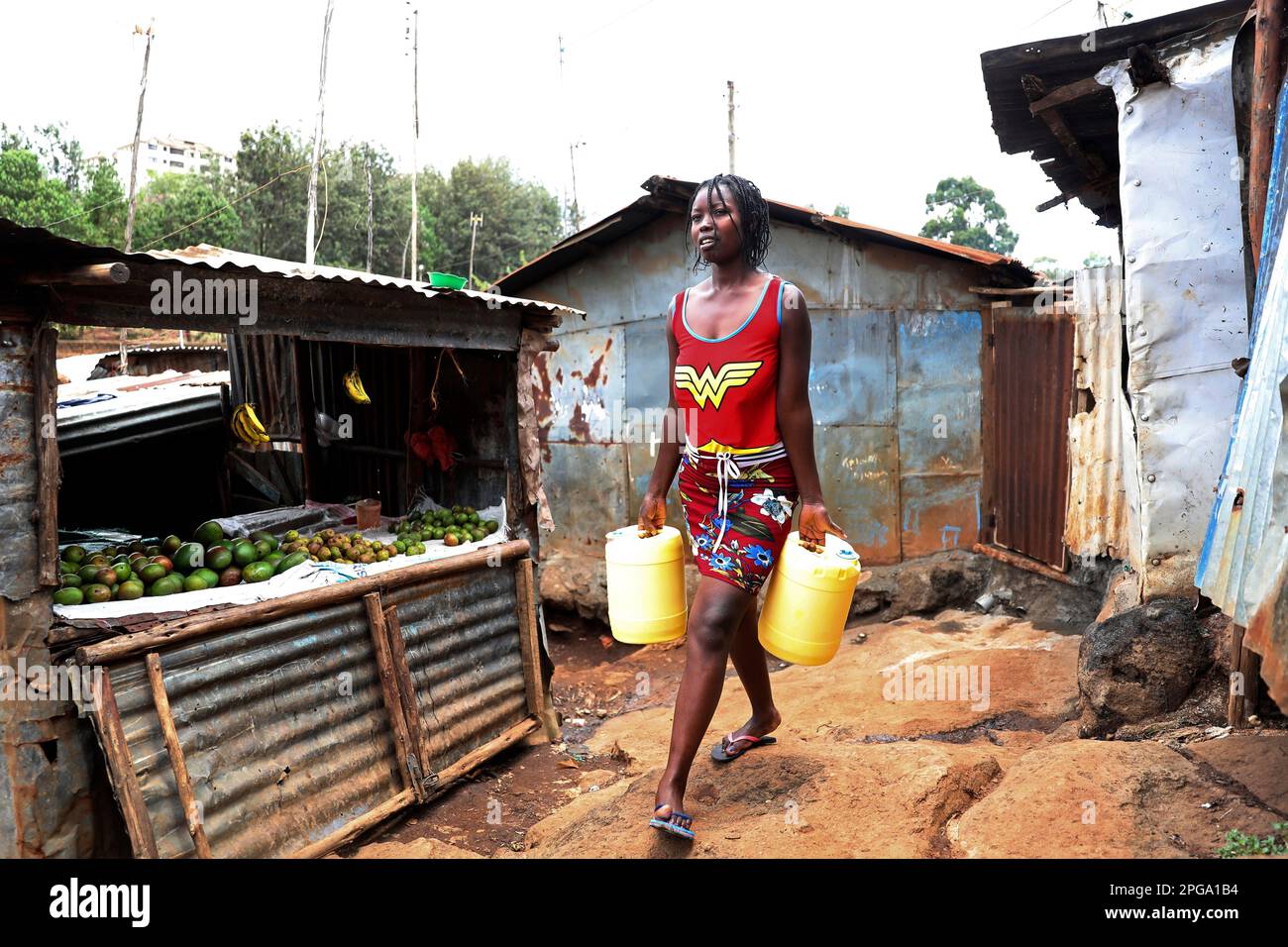 A woman carries plastic containers filled with water at the Kibera slum ...