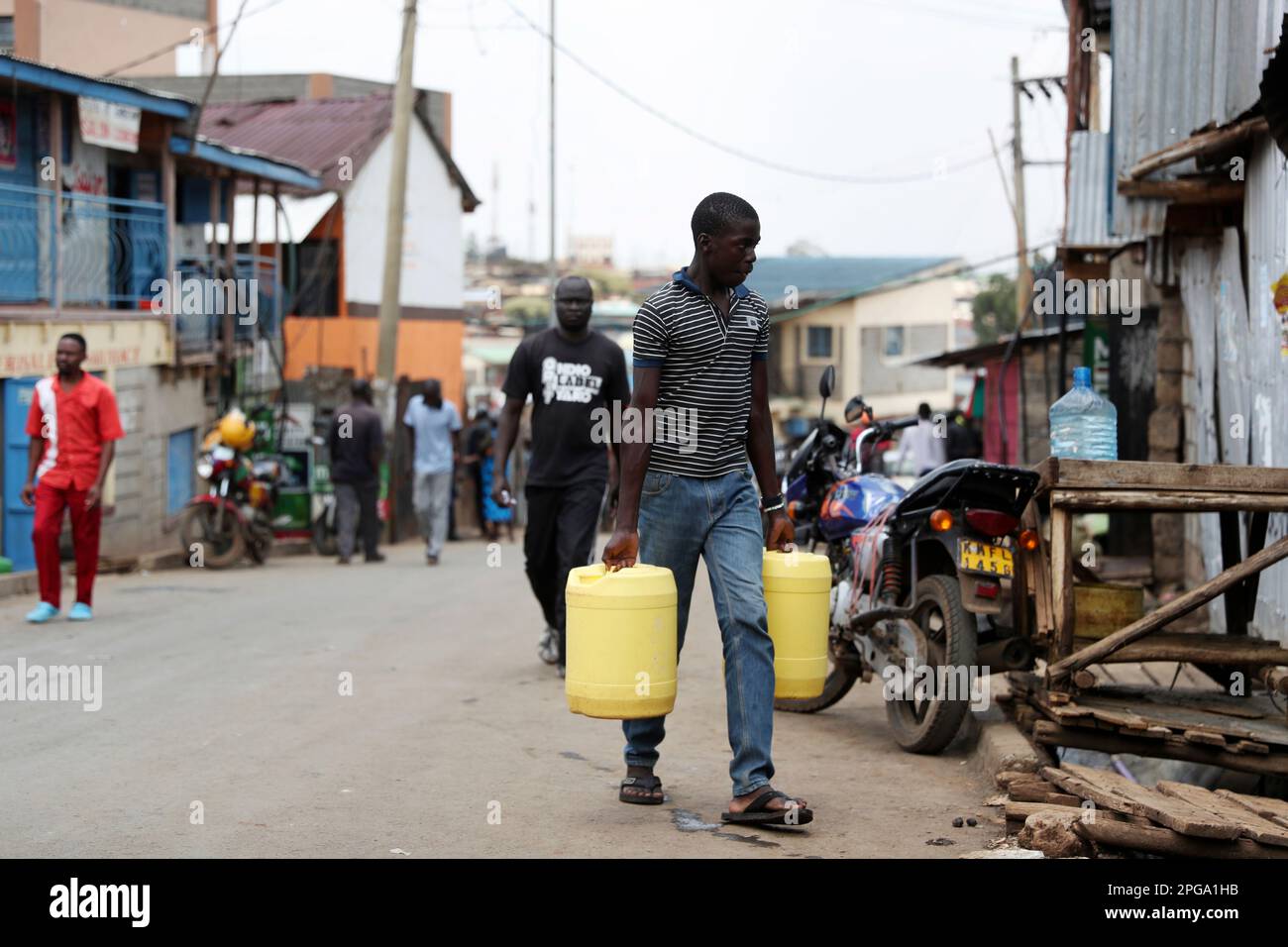 A man carries plastic containers filled with water in the Kibera slum ...