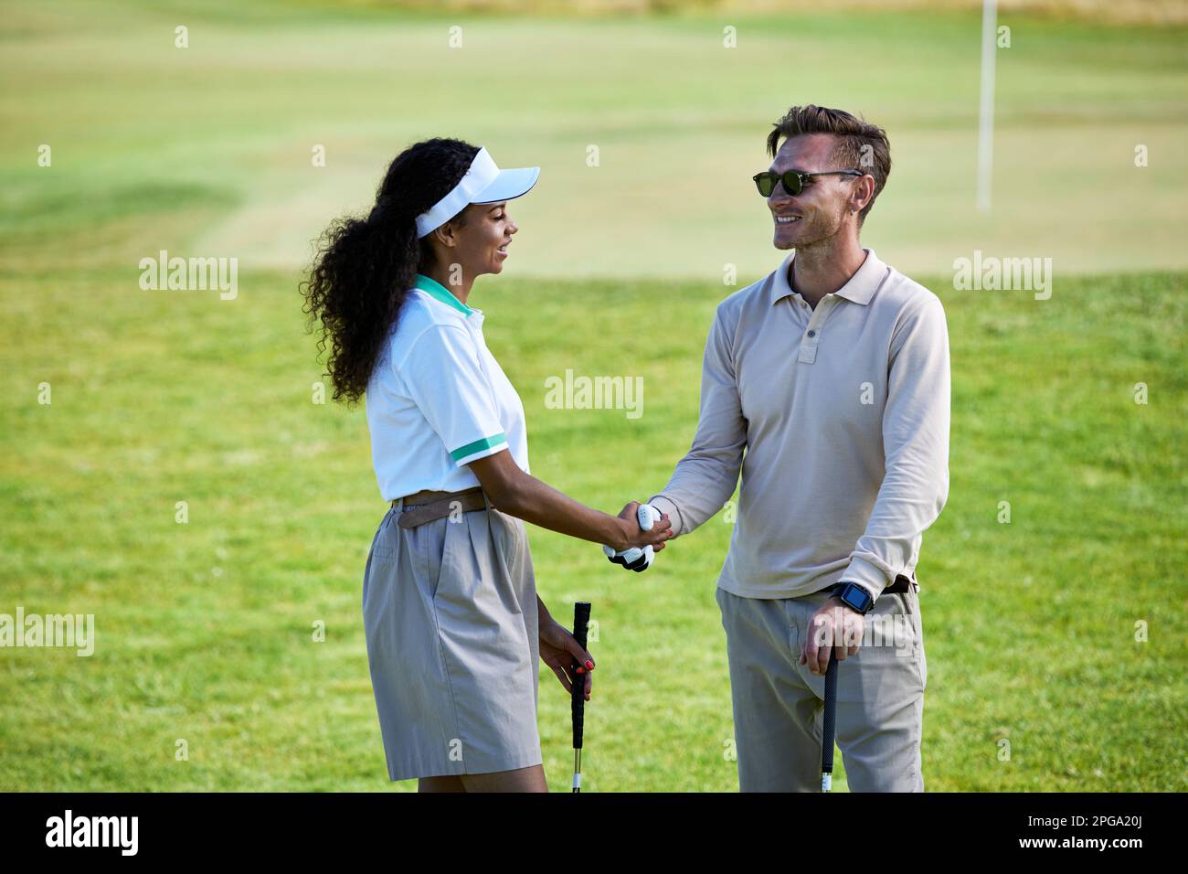 Portrait of two golf players shaking hands on green field after ...