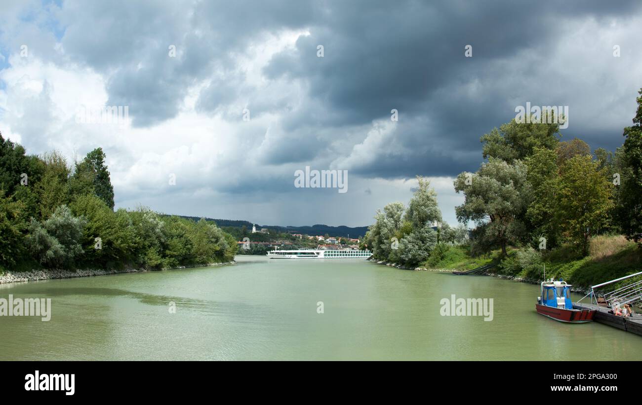 The panoramic view of dark rainy clouds over Melk town dock and a boat ...