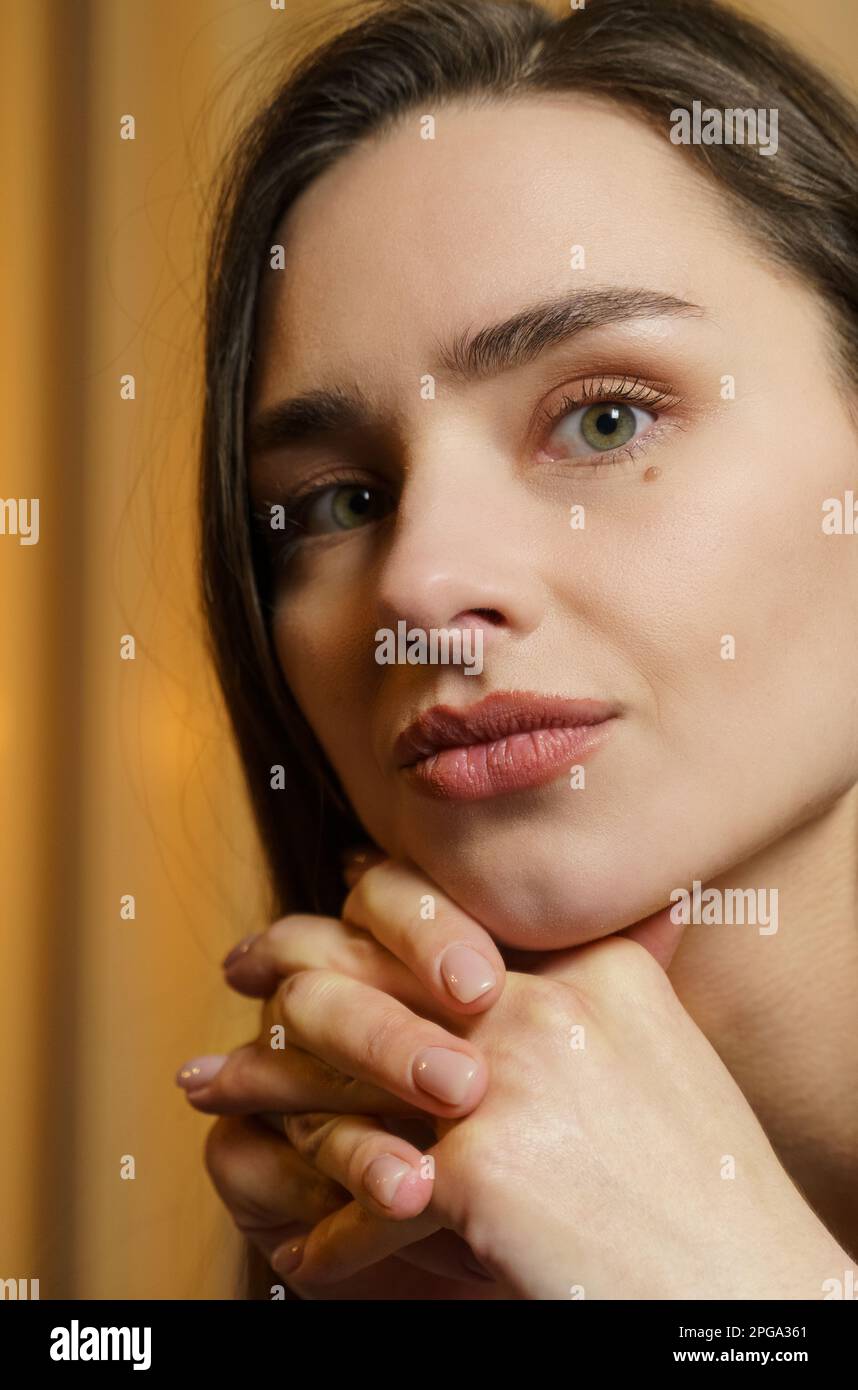 Close-up portrait of the face of a young thoughtful woman who props her ...