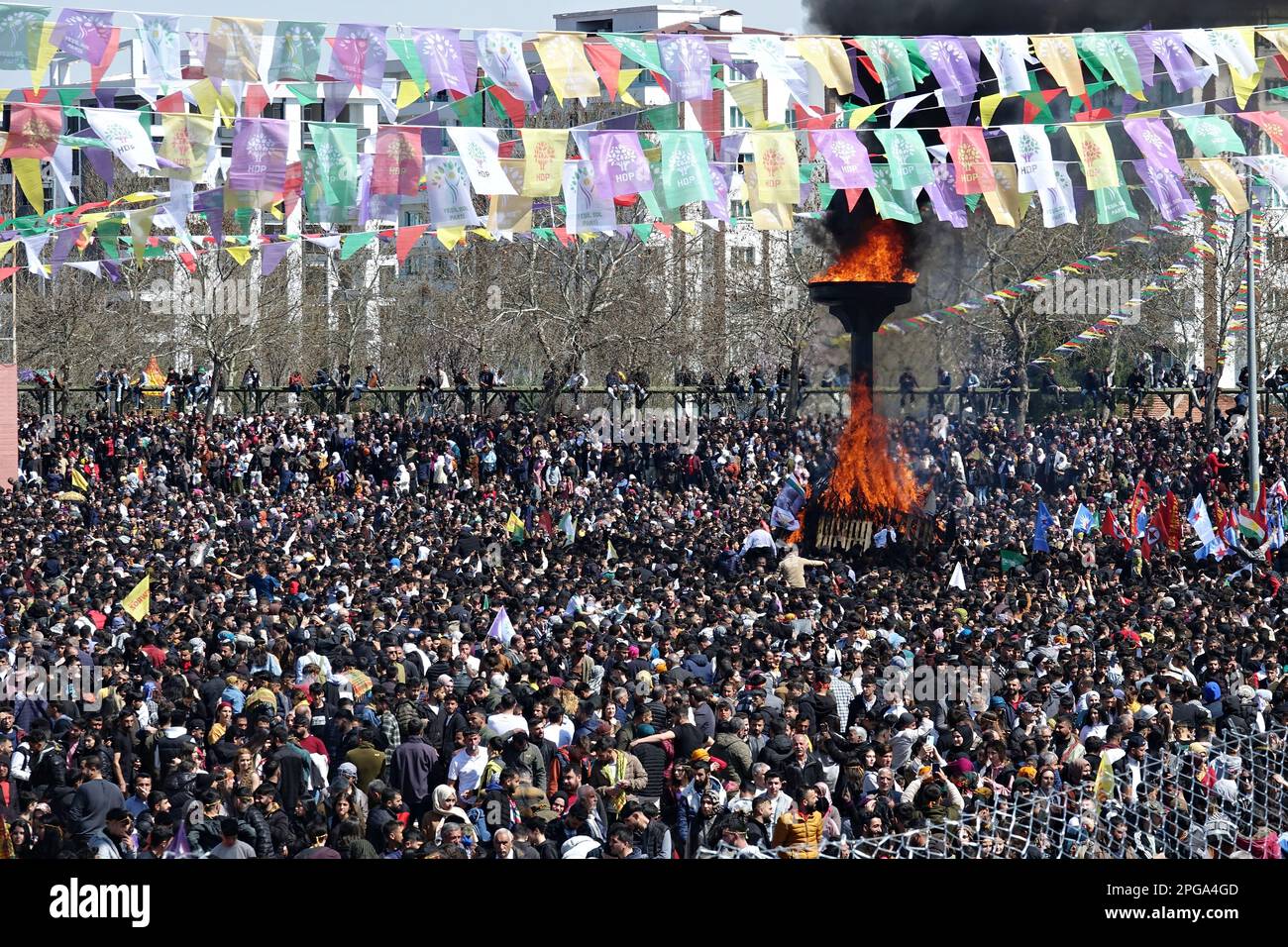 A nawroz fire is lit on a large torch with wood amid a crowd of ...
