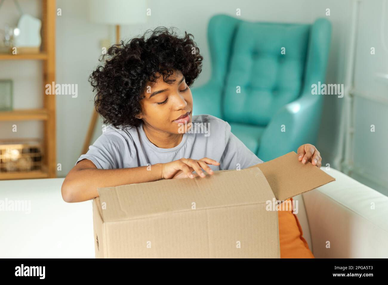African girl unpacking delivery looking in box. Happy woman opening ...