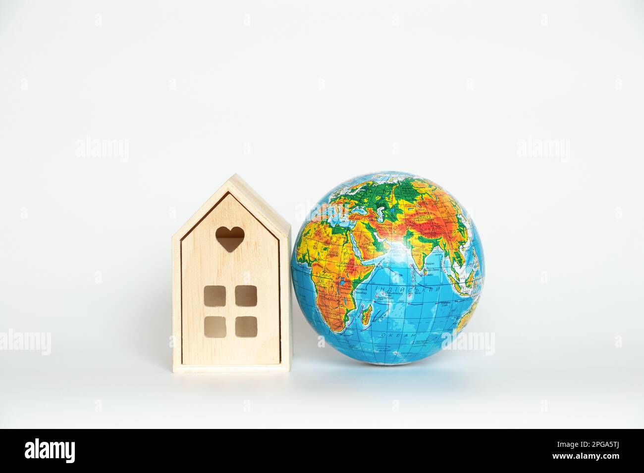 A small wooden house and a globe on a white background , place of ...