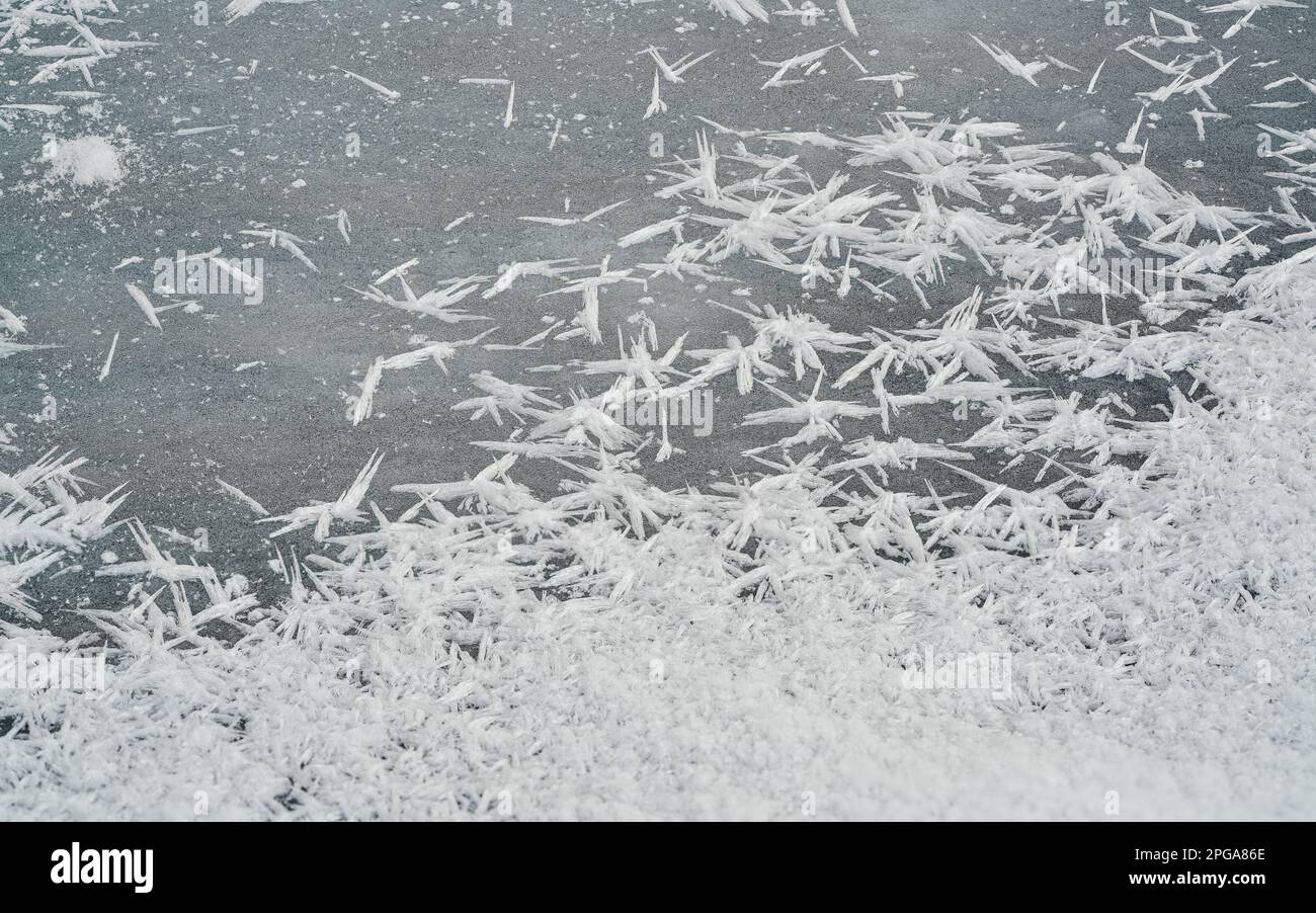 Ice crystals forming spike shapes on frozen river, closeup macro detail ...