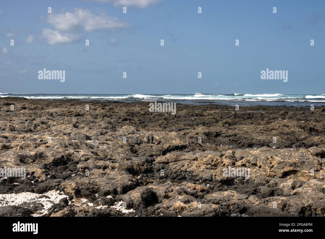 Dark rocks on the beach of Atlantic ocean. White areas filled with ...