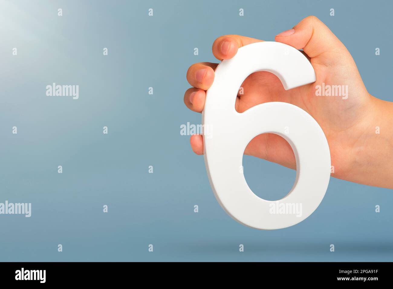 Number six in hand. A hand holds a white number 6 on a blue background ...