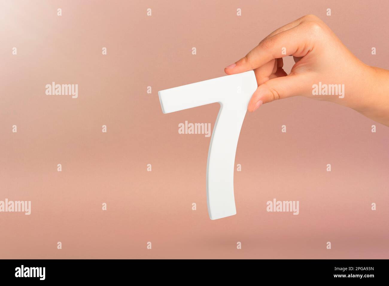 Number seven in hand. Hand holding white number 7 on red background ...