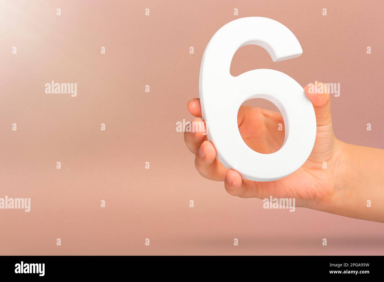 Number six in hand. A hand holds a white number 6 on a red background ...