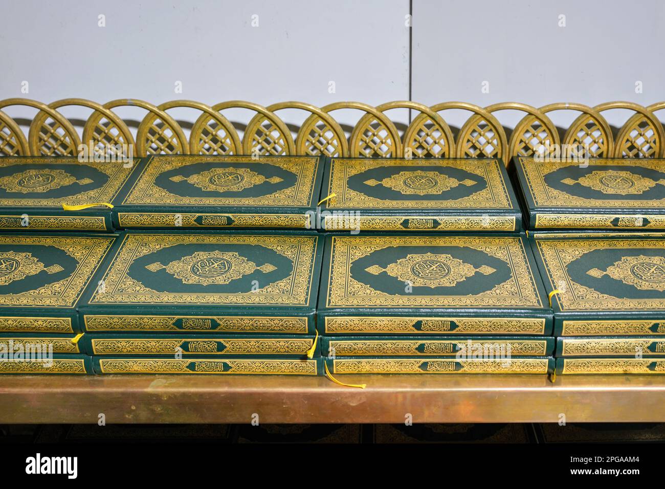 Stacks of green and golden Quran or Quraan books at shelf, closeup ...