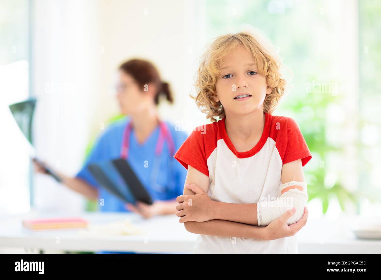 Child with arm injury at trauma and emergency care. Kid with elbow cast at health clinic. Doctor ...