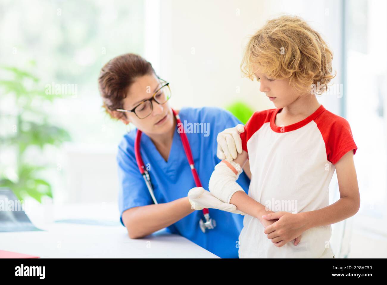 Child with arm injury at trauma and emergency care. Kid with elbow cast at health clinic. Doctor ...