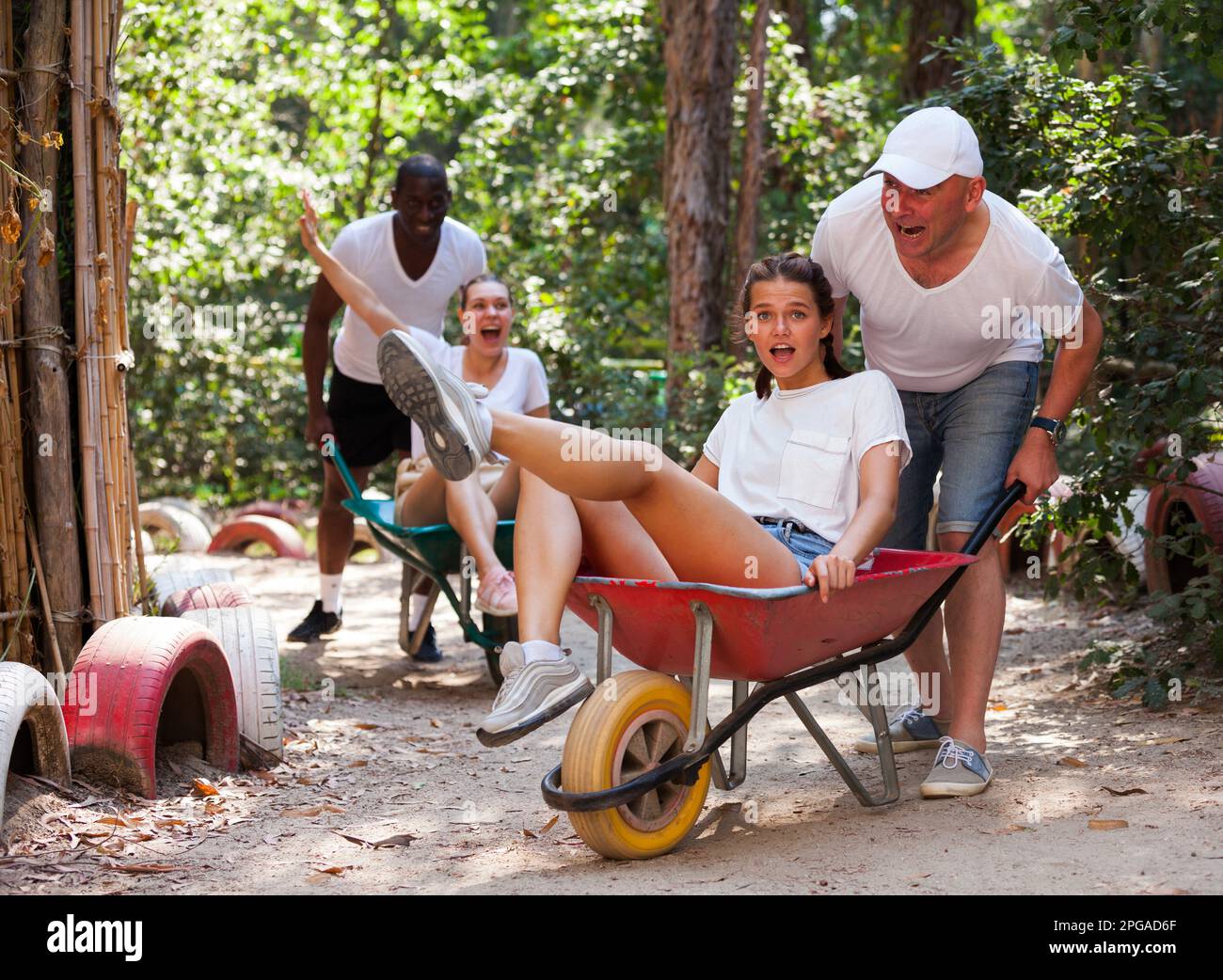Men drive their girls in garden wheelbarrows. Funny amusement park amusement park Stock Photo ...