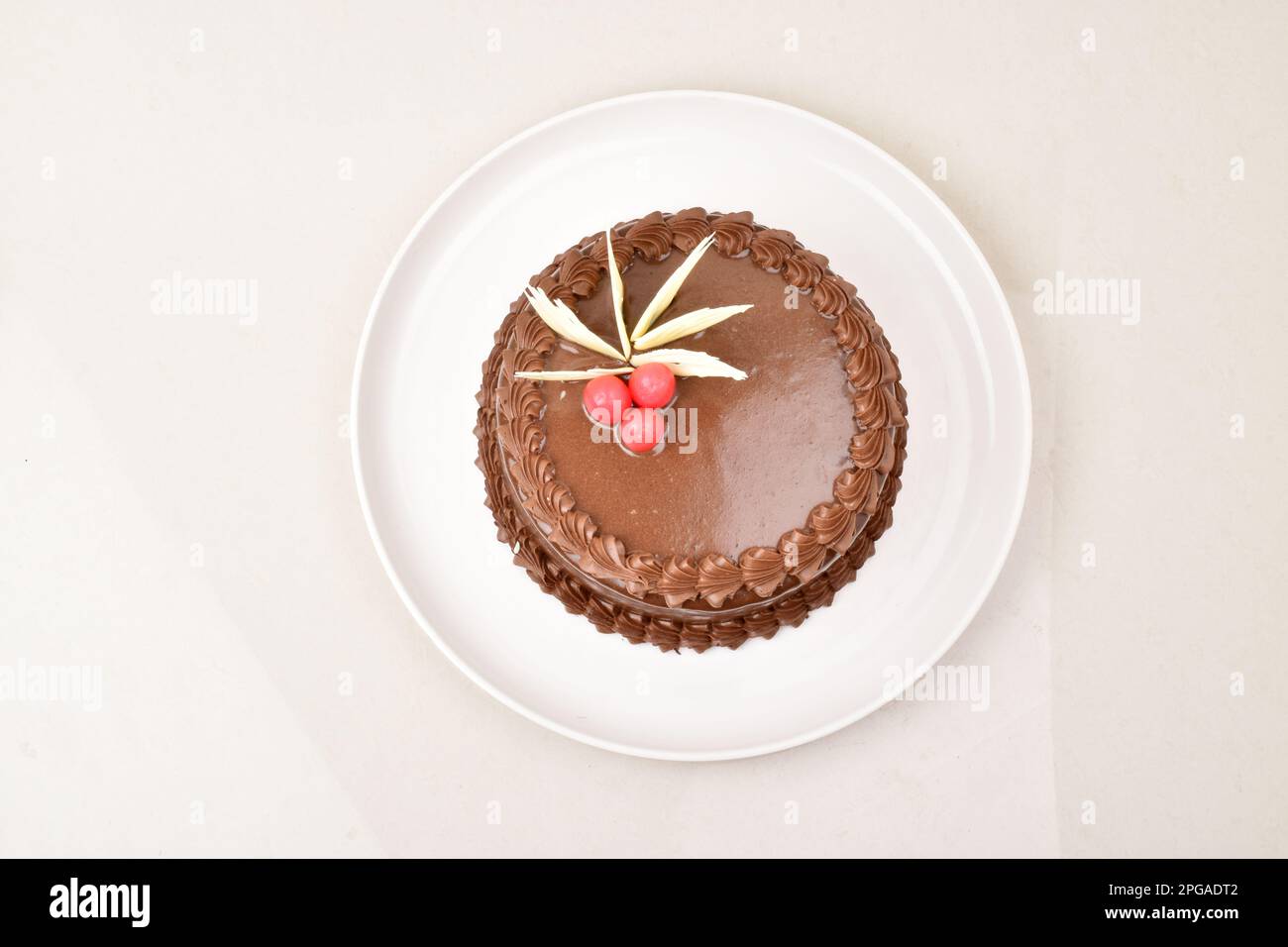 Top view of whole chocolate cake in plate isolated on white background ...